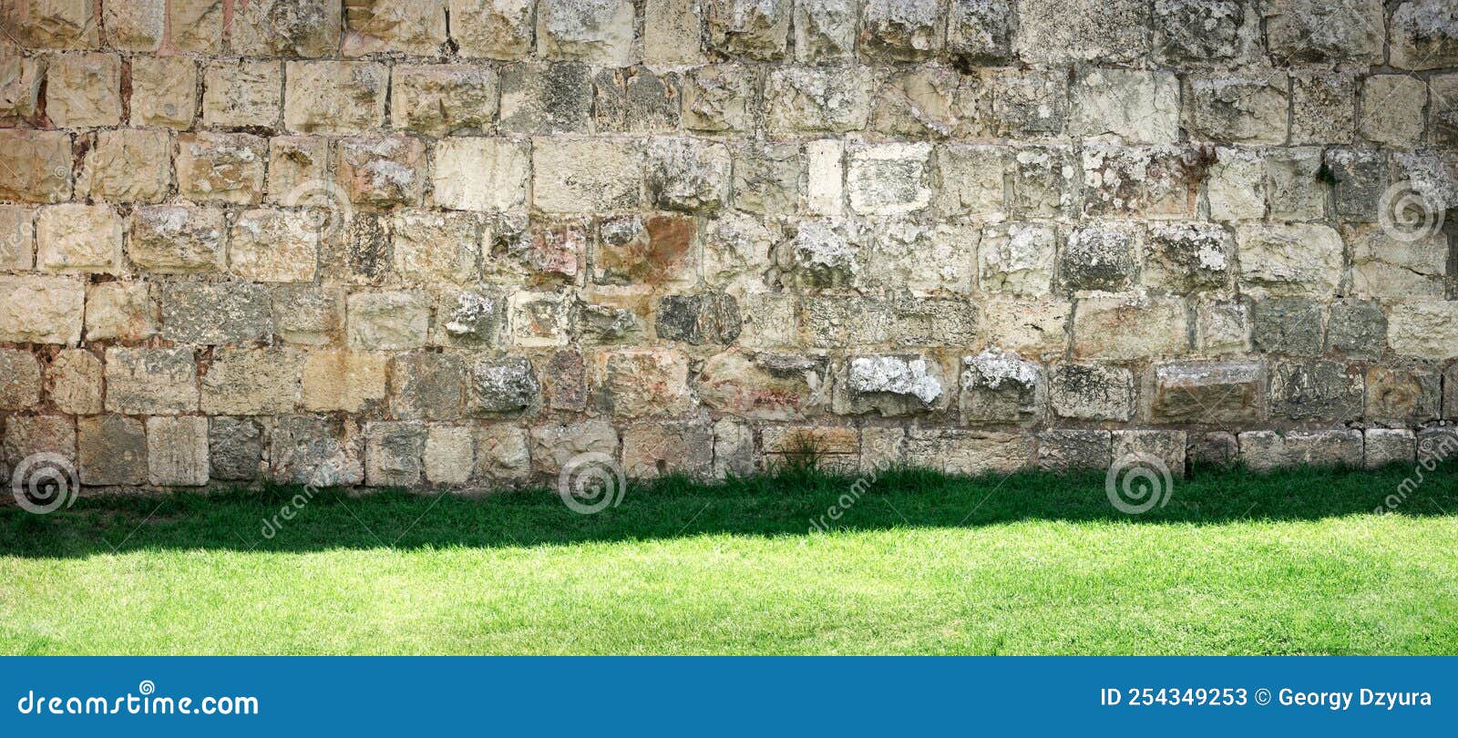 Background with an Ancient Wall and Green Grass Lit by the Sun Stock ...