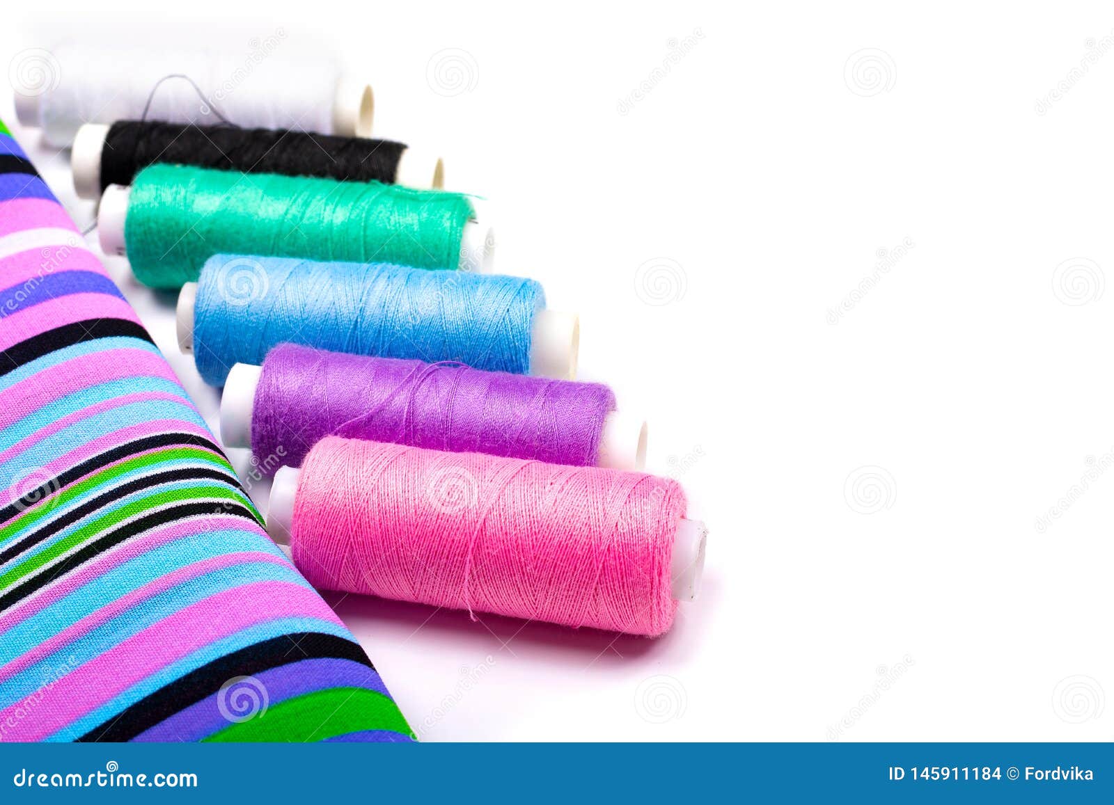 Background of Striped Fabric and Spools of Threads of Different Colors ...