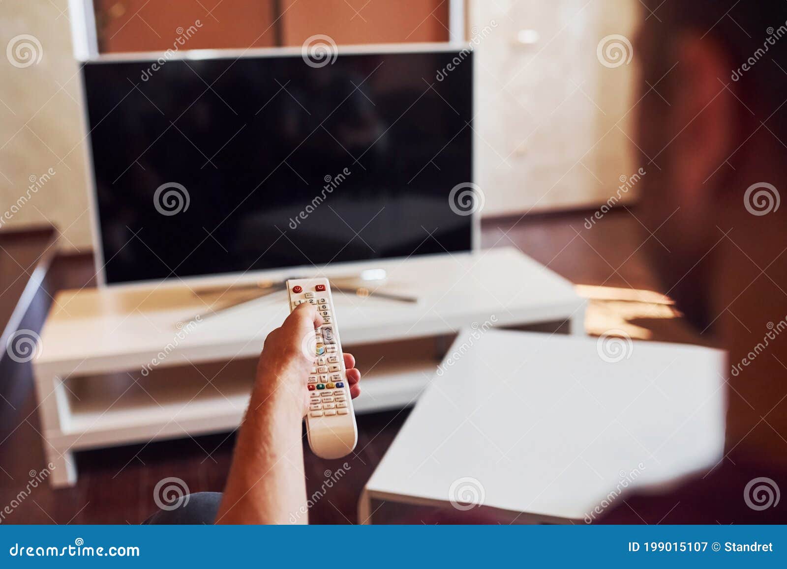 Backing View of Man Holds Remote Controller in Hand and Turning on TV ...