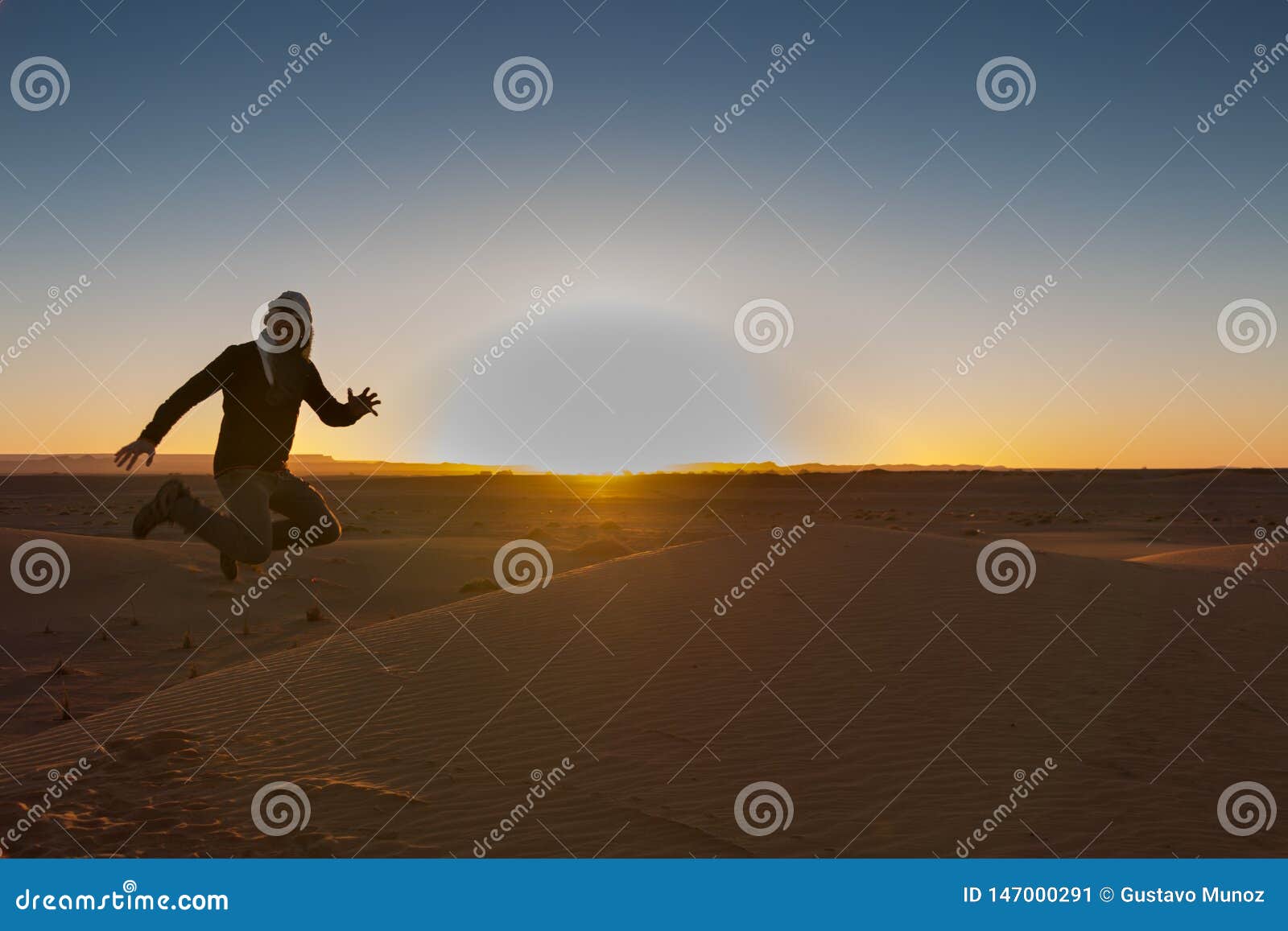 A Backlit Man Jumps Happily in the Erg Chebbi Desert at Dawn Stock ...