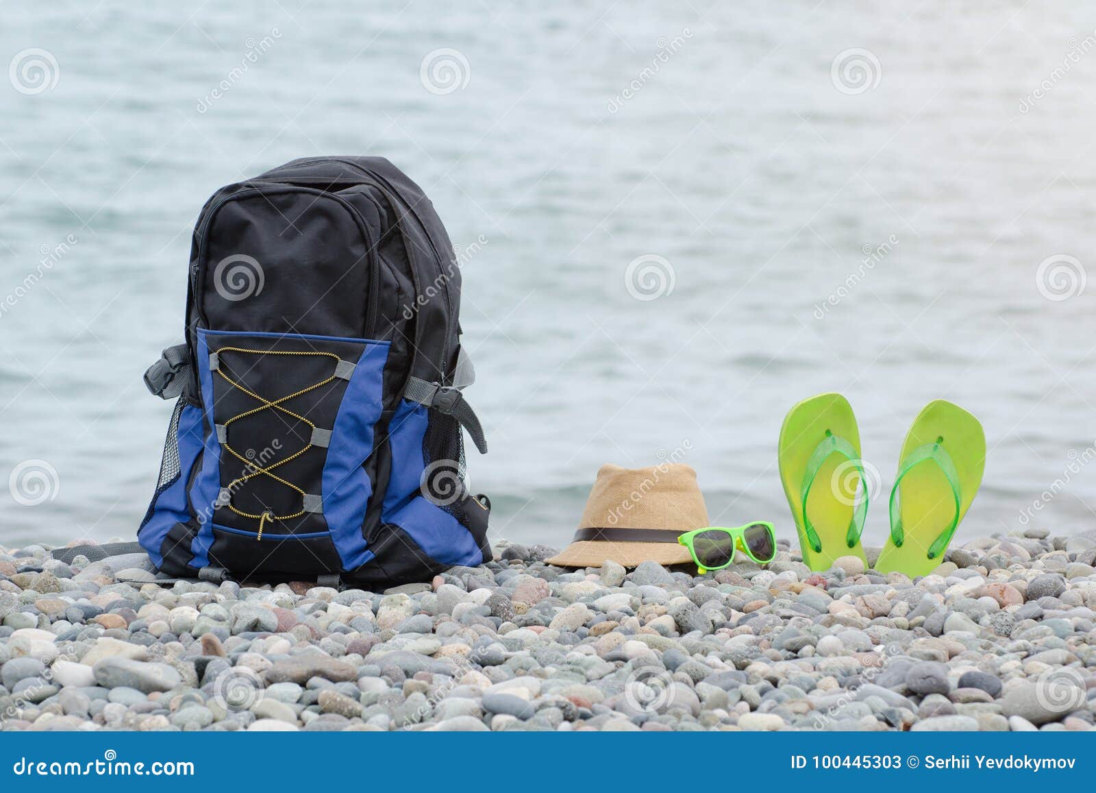 Backpack, Hat and Flip-flops and Glasses on the Pebble Beach. Sea in ...