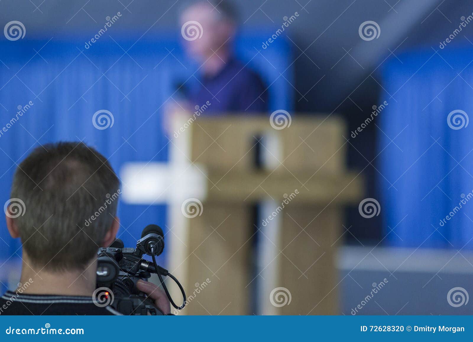 Backview of Professional Cameraman Capturing a Spokesperson Speaking on ...