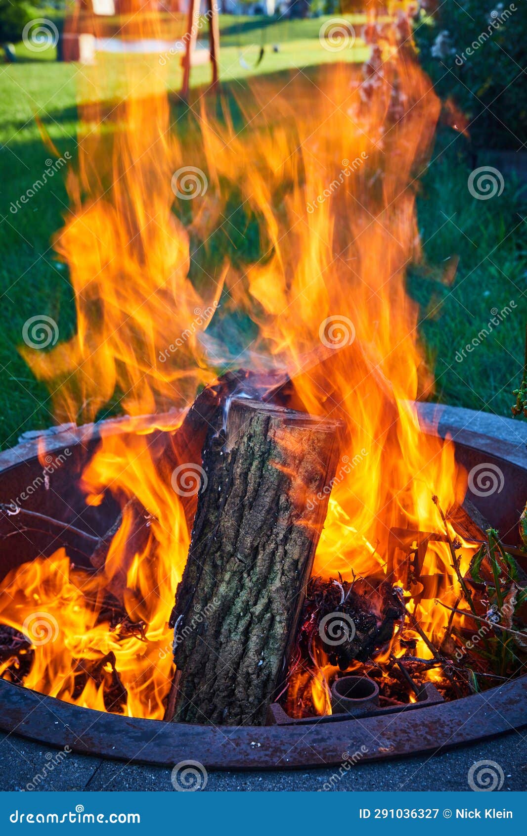 Backyard Fire Pit with Green Lawn in Round Pit with Tall Orange and ...