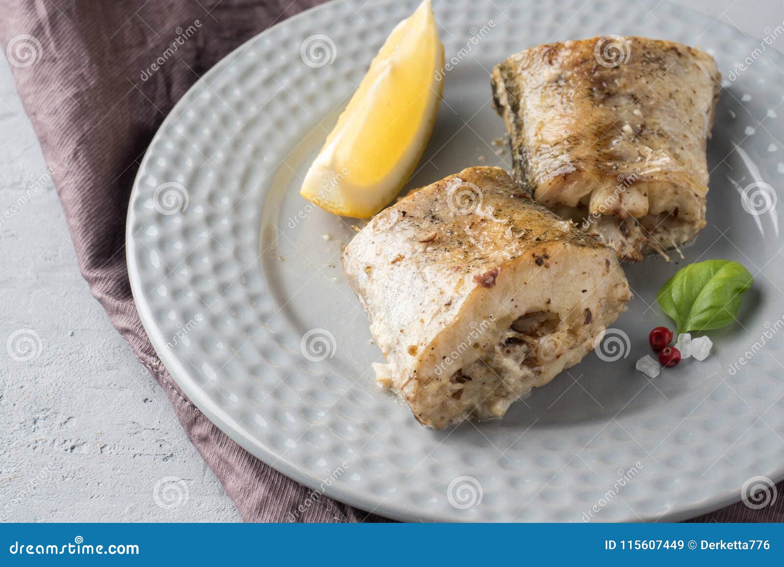 Baked Pollock Fish with Lemon and Spices on a Plate Napkin on the Table ...