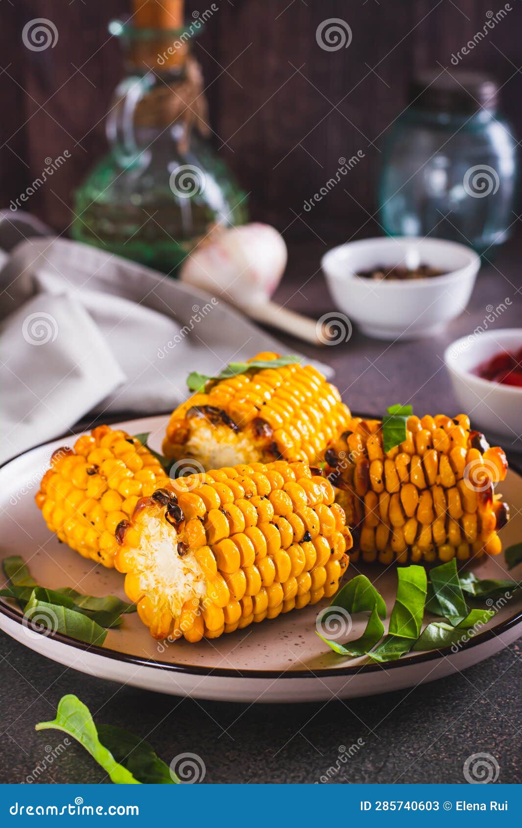 Baked Sweet Corn Cobs with Butter, Garlic and Herbs on a Plate Vertical ...