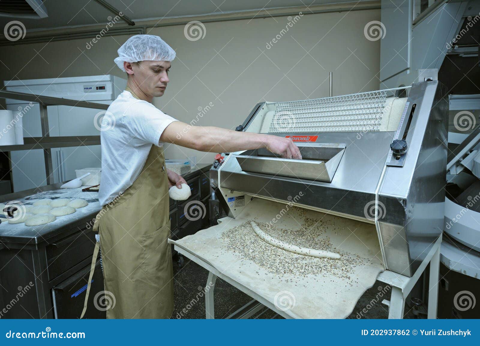At the Bakery: Baker Standing at a Dough Forming Machine and Forming ...