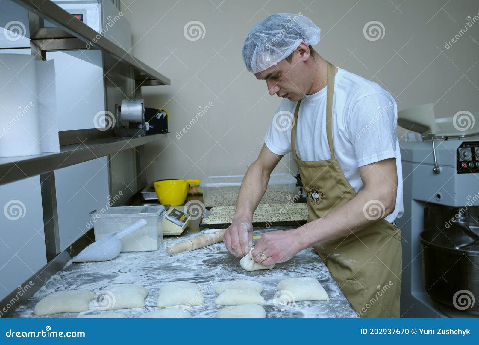 At the Bakery: Baker Standing at a Work Table and Molding Dough for ...