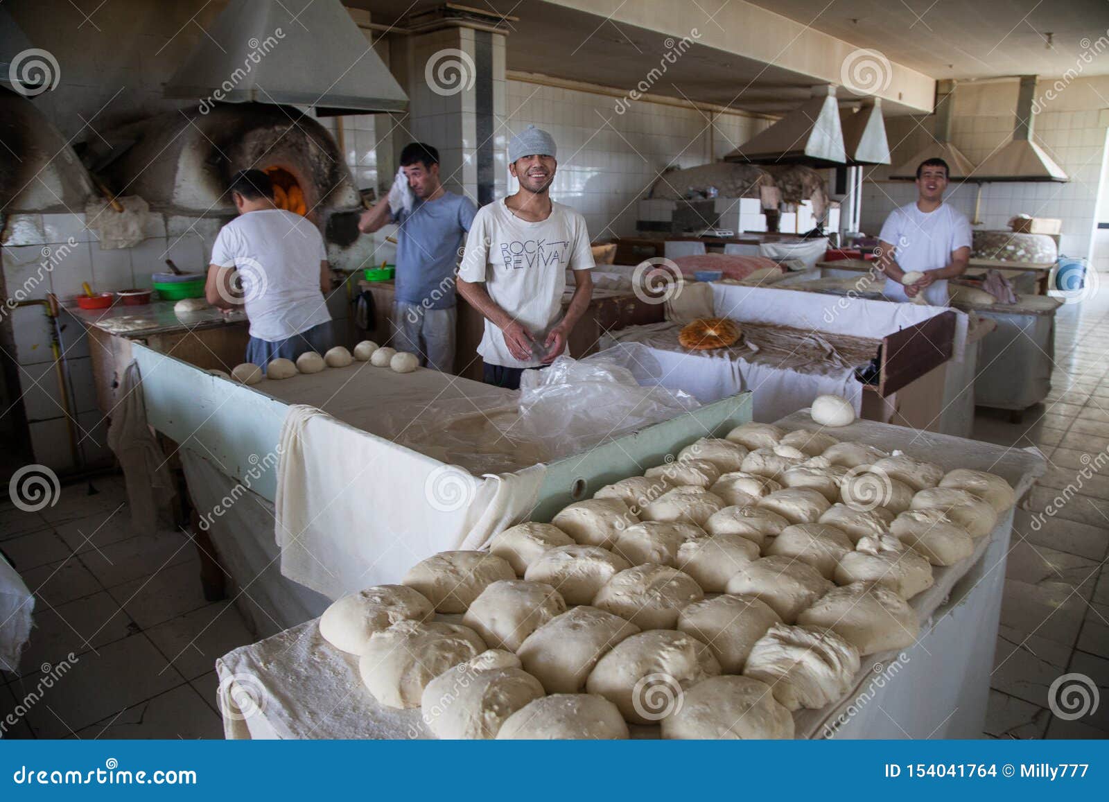 In Bakery Two Bakers Put Loaves Of Bread On A Baking Tray Editorial ...