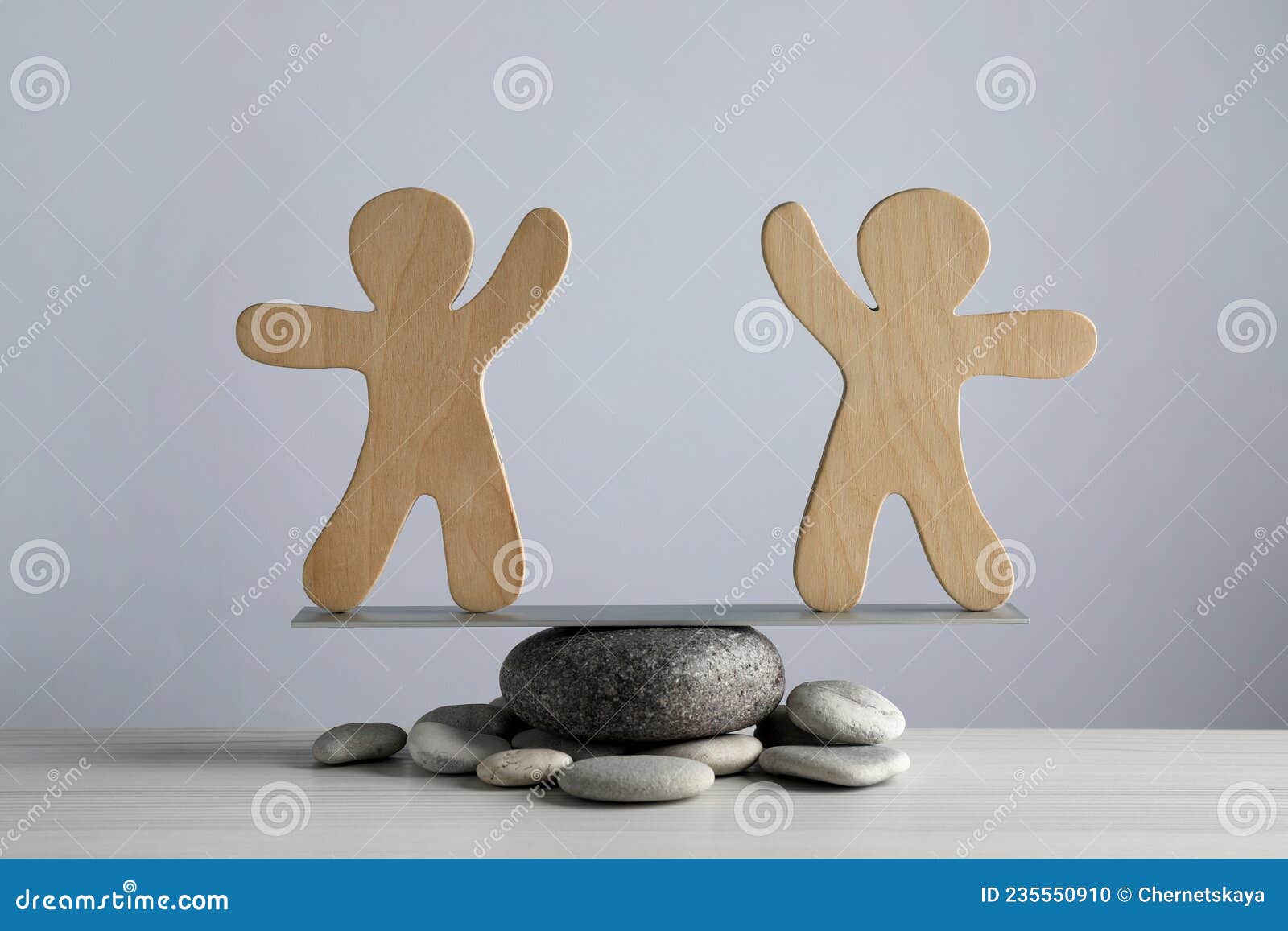 Balancing Wooden Human Figures on Stones Against Light Grey Background ...