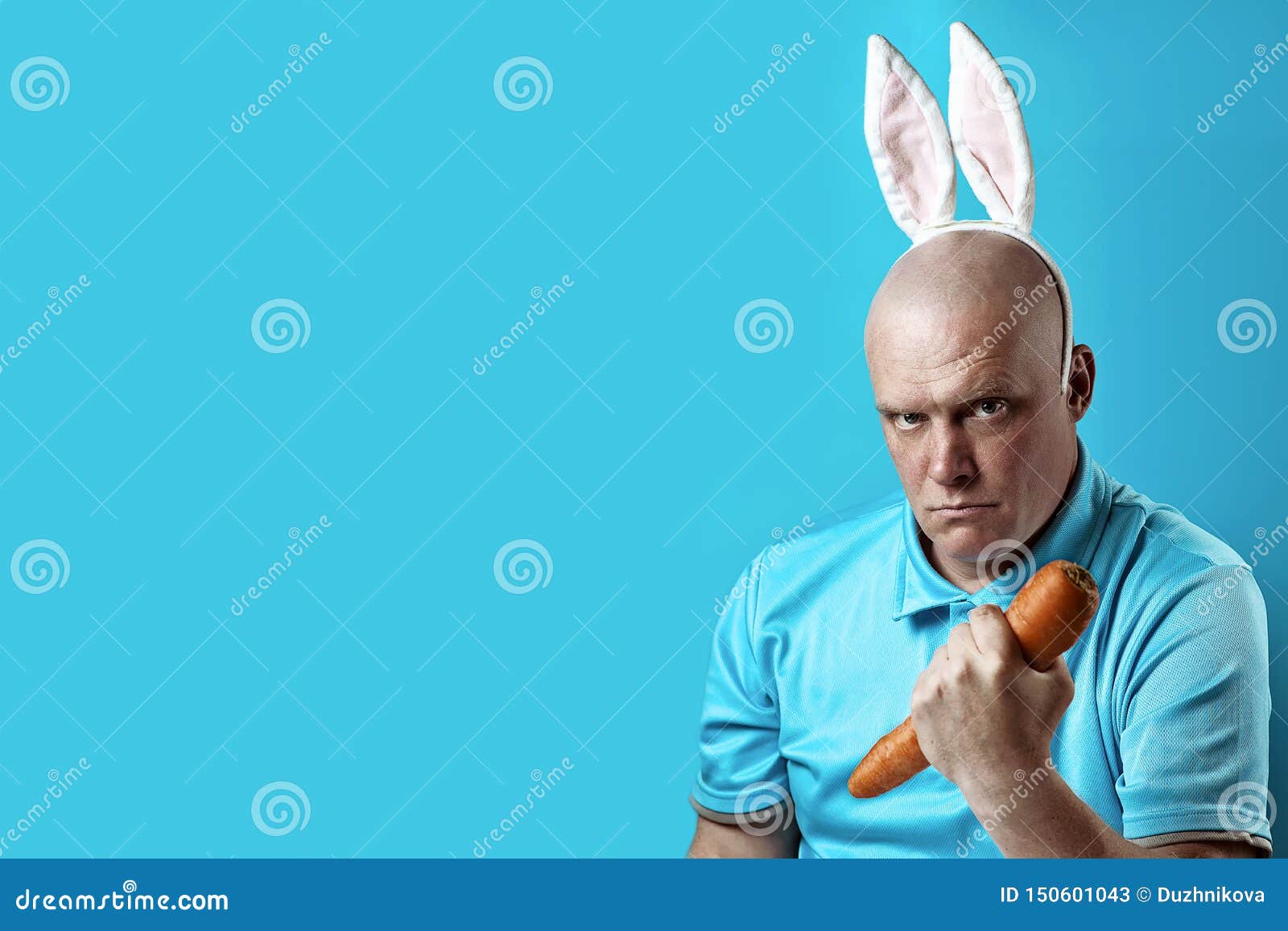 Bald Brutal Man in Light T-shirt and Rabbit Ears. in His Hands he Holds ... Bald Brutal Man in Light T-shirt and Rabbit Ears. in His Hands he Holds ...