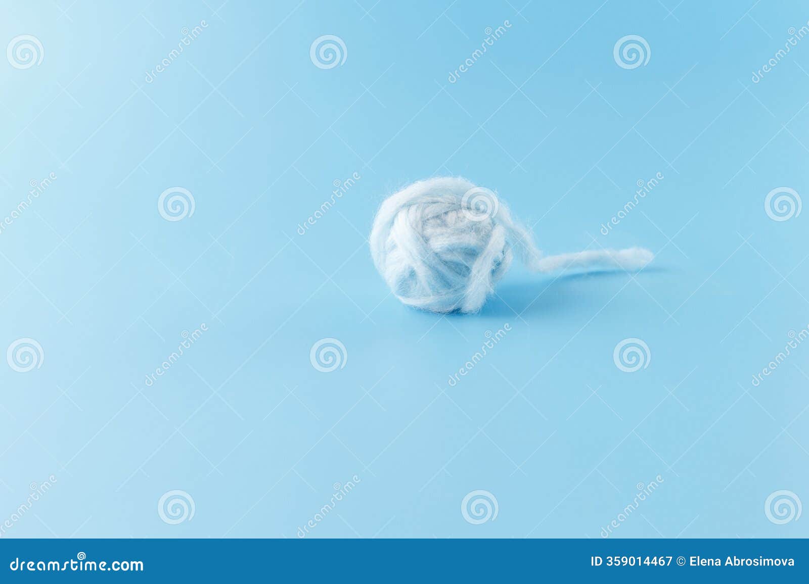 A Ball of Light Blue Yarn Resting on a Slightly Lighter Blue Surface ...