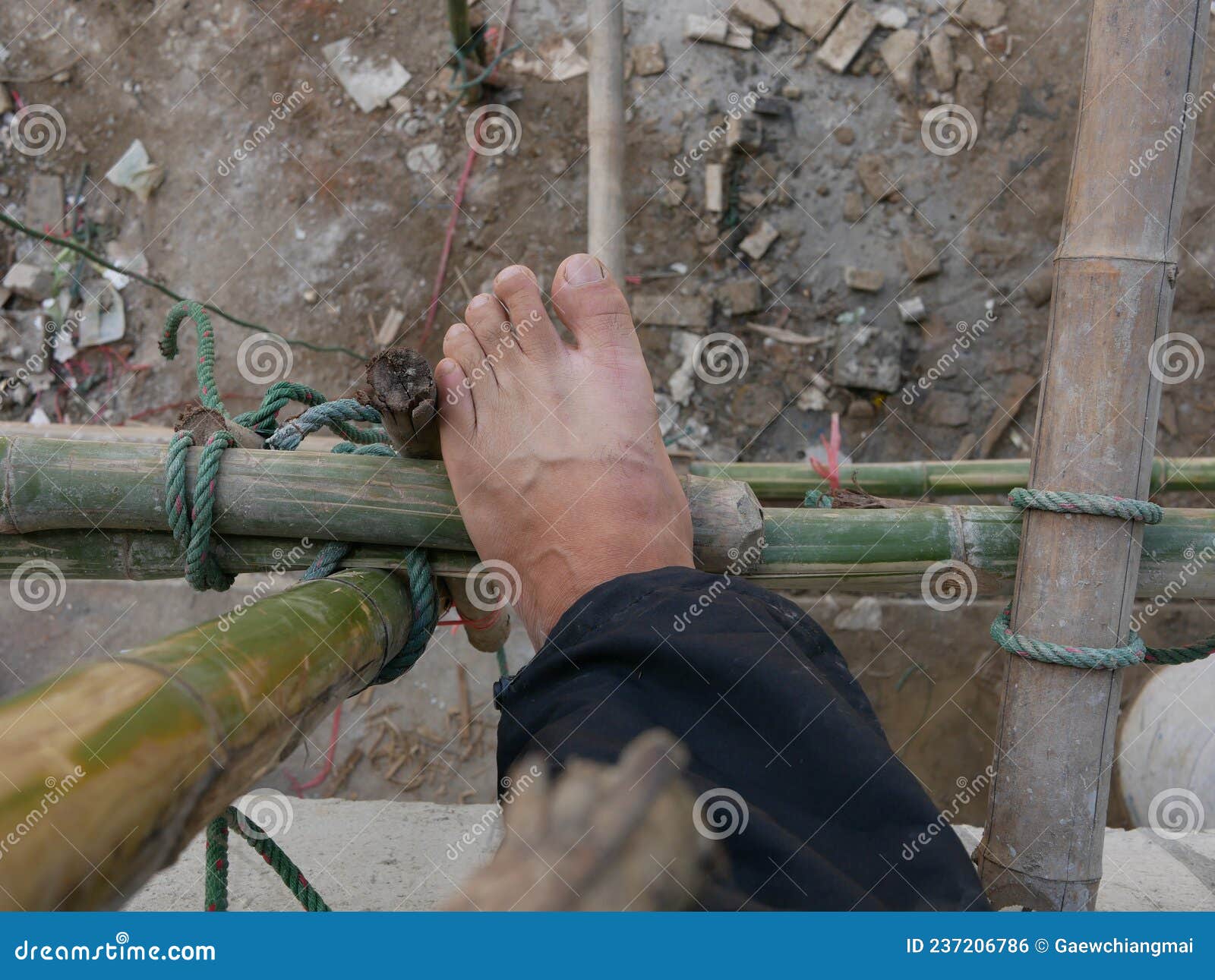 Bare Foot of a Worker Above the Ground on Bamboo Scaffolds that are ...