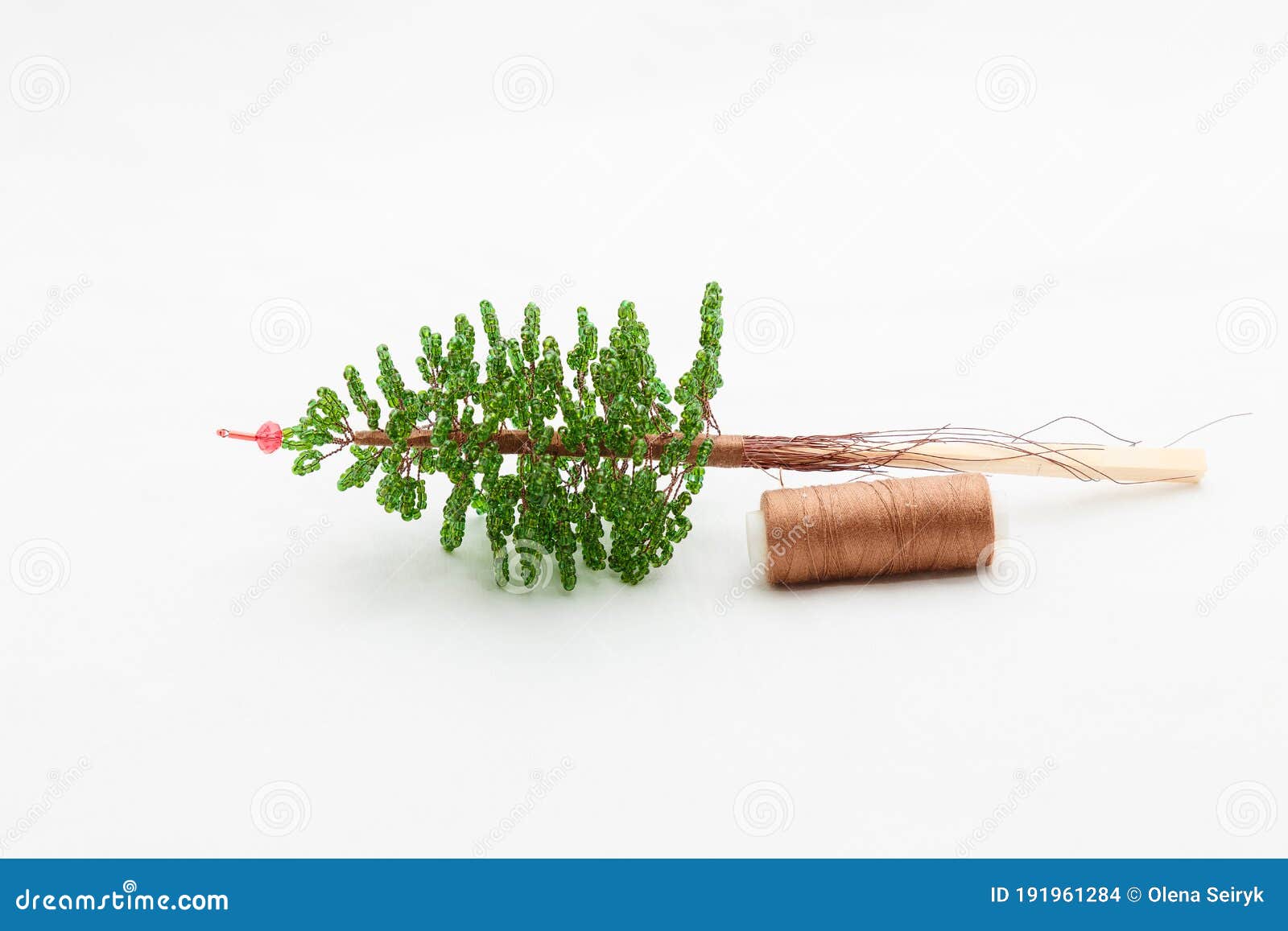 Beaded Fir Tree Branch and Brown Threads Spool on White Fabric ...