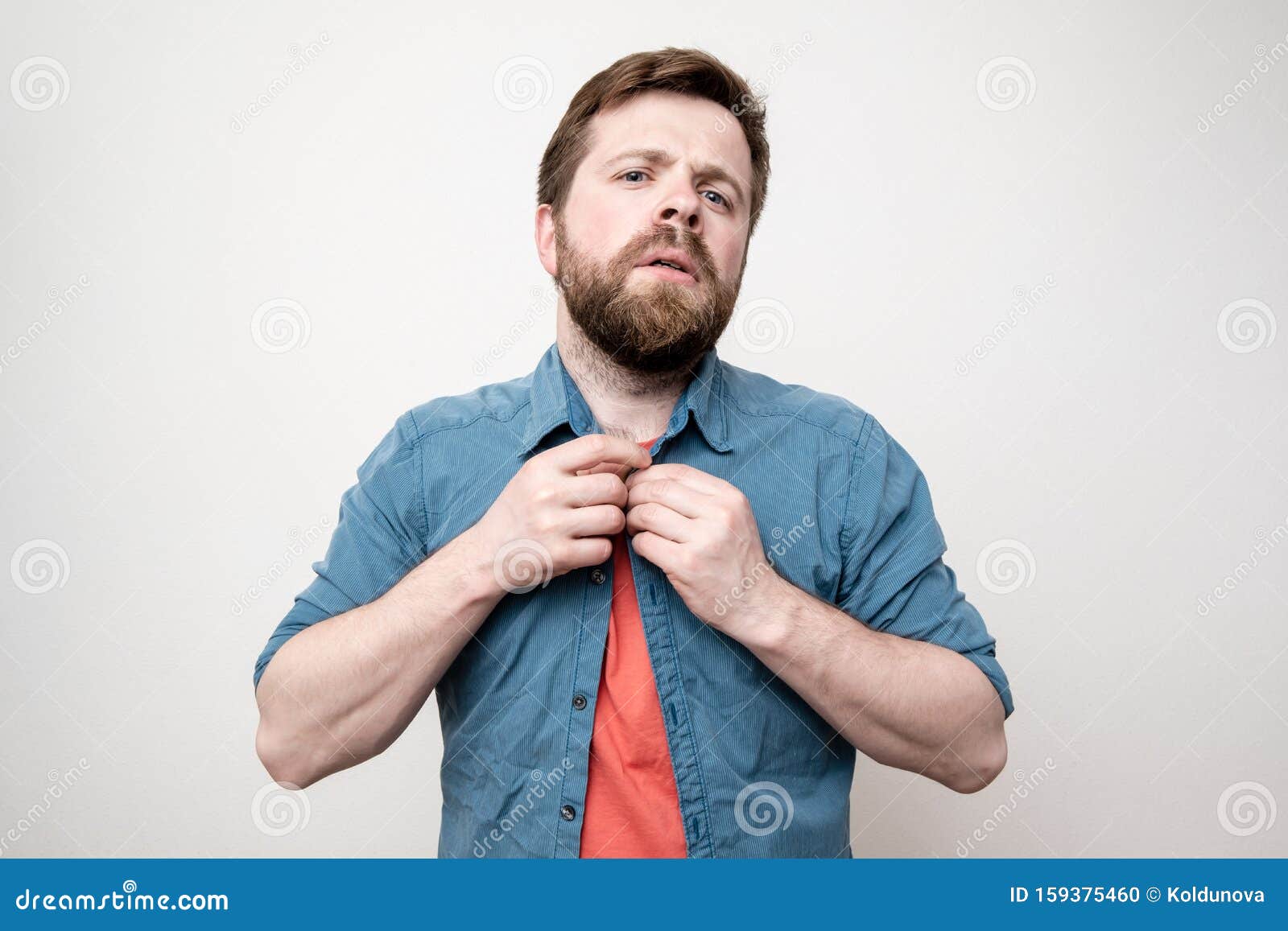 Bearded Man Fastens Buttons On His Shirt And Looks Haughtily At The