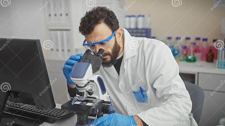 A Bearded Man in a Lab Coat Using a Microscope in a Laboratory Setting ...