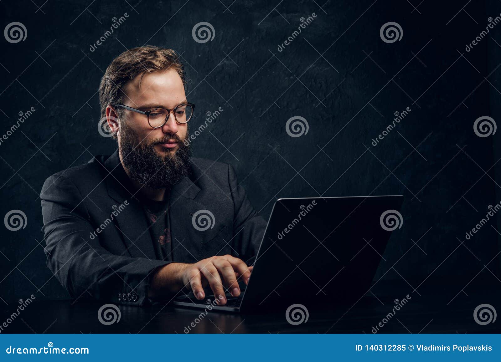 Bearded Programmer Working on Laptop Sitting at the Table in Office ...