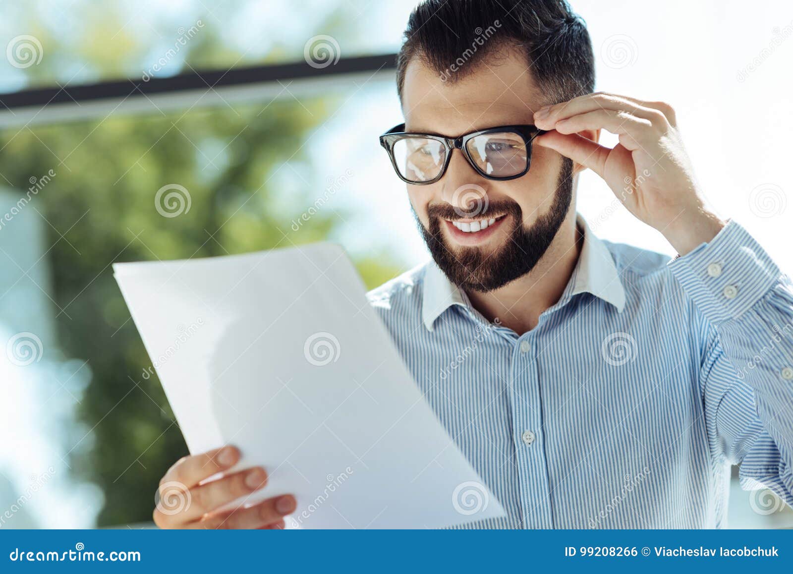 Bearded Young Man Looking at Documents and Smiling Stock Photo - Image ...