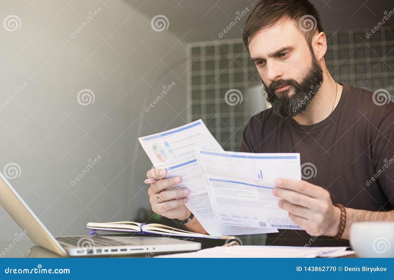 Bearded Young Man Sitting at Table Looking at Documents and Thinking ...