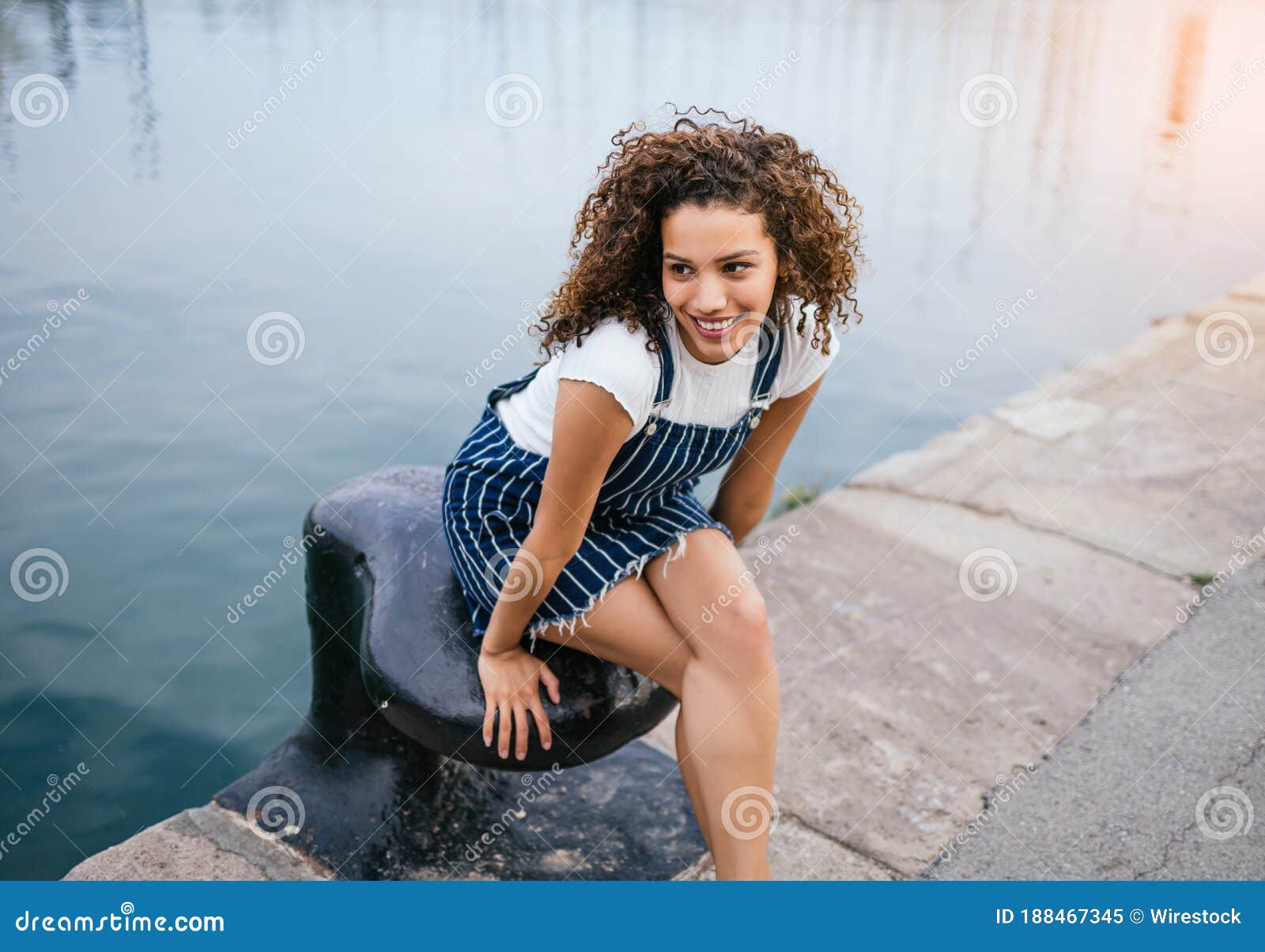 Beautiful African American Woman Sitting On A Mooring Beside A Lake