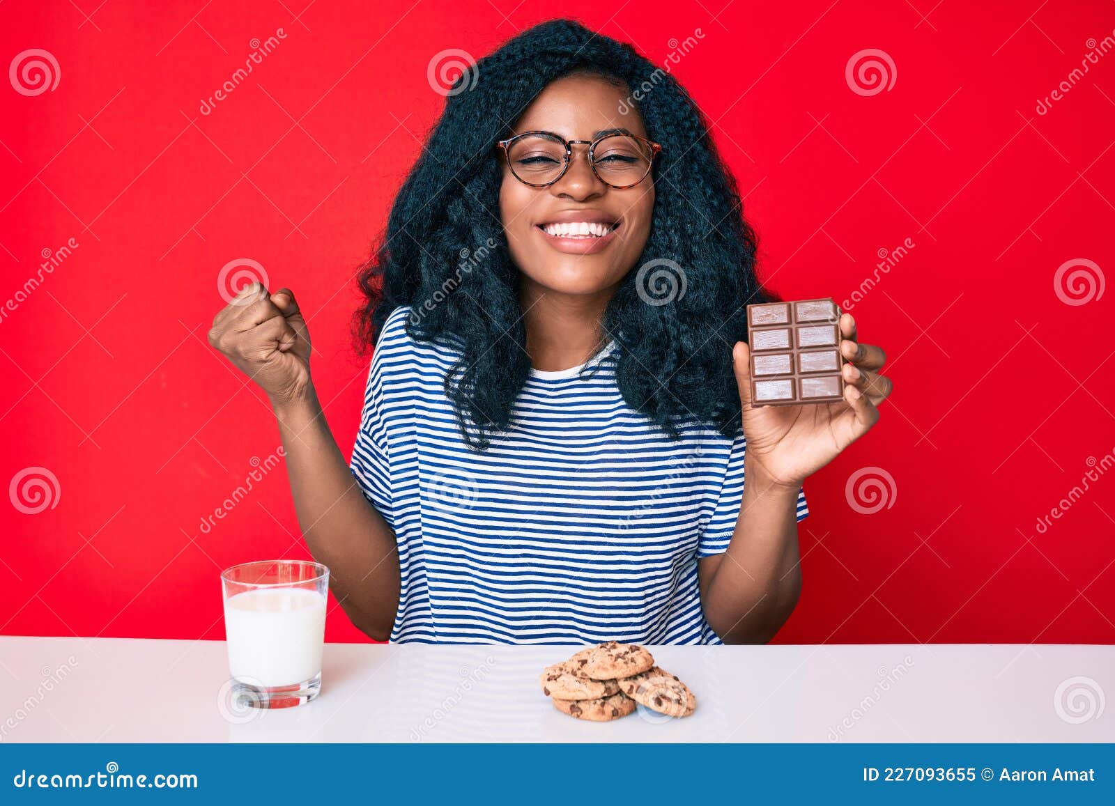 Beautiful African Woman Eating A Chocolate Bar And Drinking Glass Of