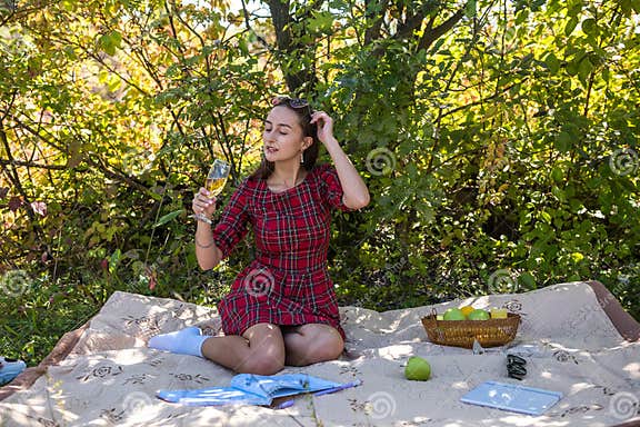 Beautiful Alone Woman In Red Dress Sitting On Picnic Blanket In Park