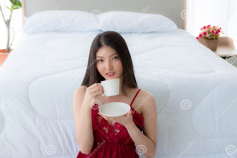 Beautiful Asian Girl Wearing Red Pajamas Sitting In The White Bedroom