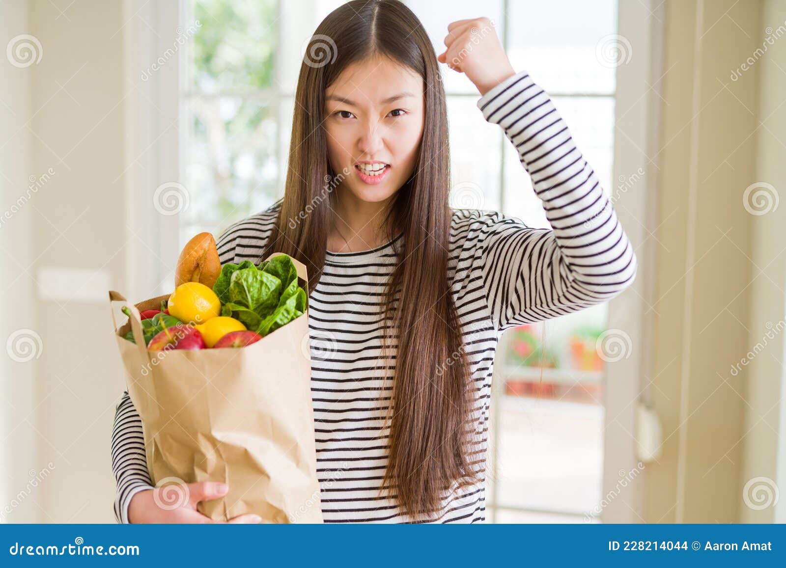 Beautiful Asian Woman Holding Paper Bag Of Fresh Groceries Annoyed And