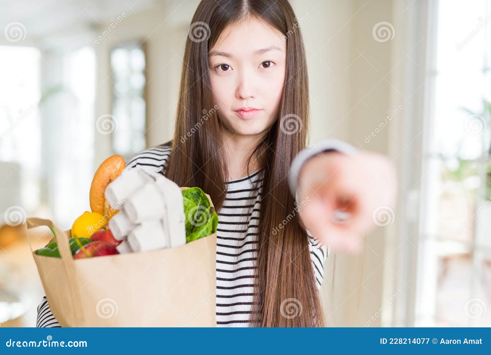 Beautiful Asian Woman Holding Paper Bag Of Fresh Groceries Pointing