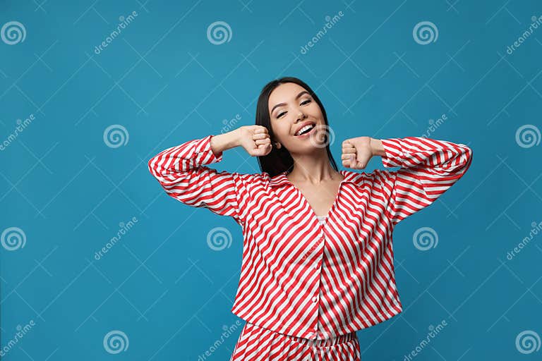 Beautiful Asian Woman In Pajamas Stretching On Background Bedtime