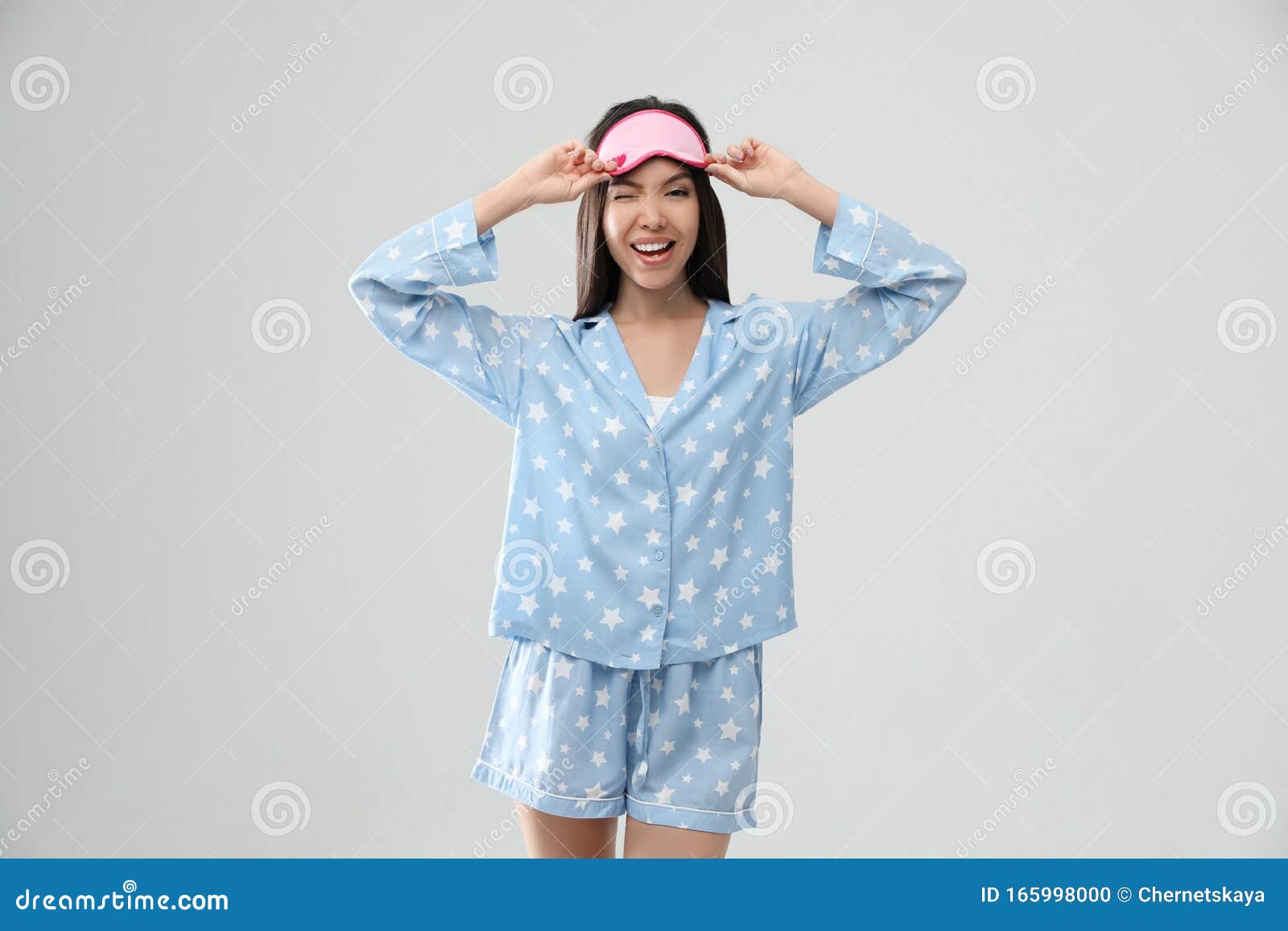 Beautiful Asian Woman Wearing Pajamas And Sleeping Mask On Grey