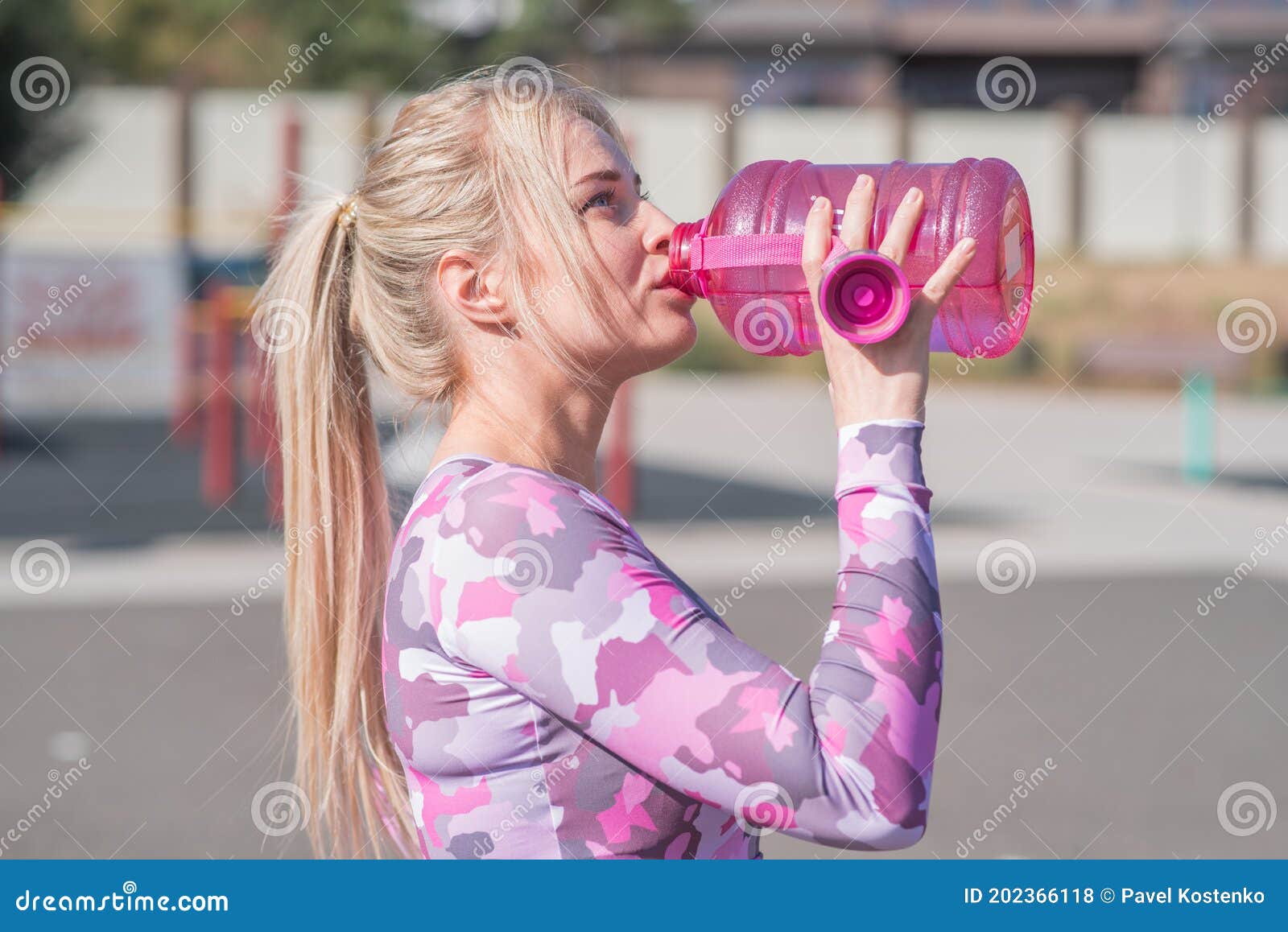 Beautiful And Athletic Blonde Girl Drinks Water After Jogging Stock