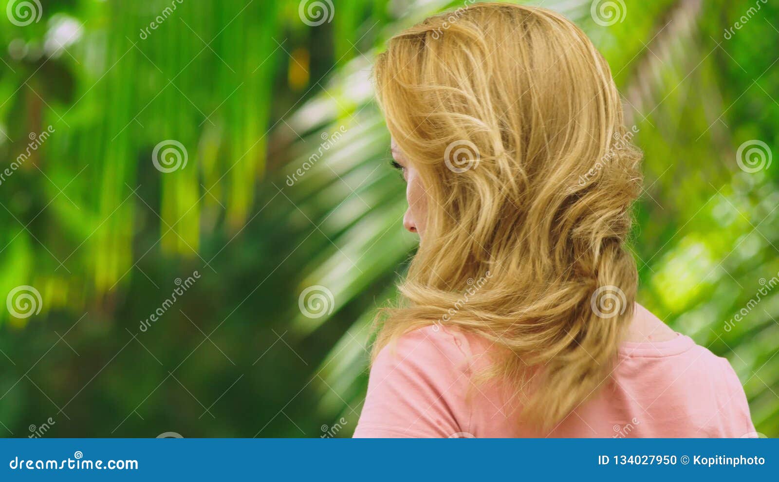 Beautiful Blond Woman Touches Her Hair In Nature Back View Stock