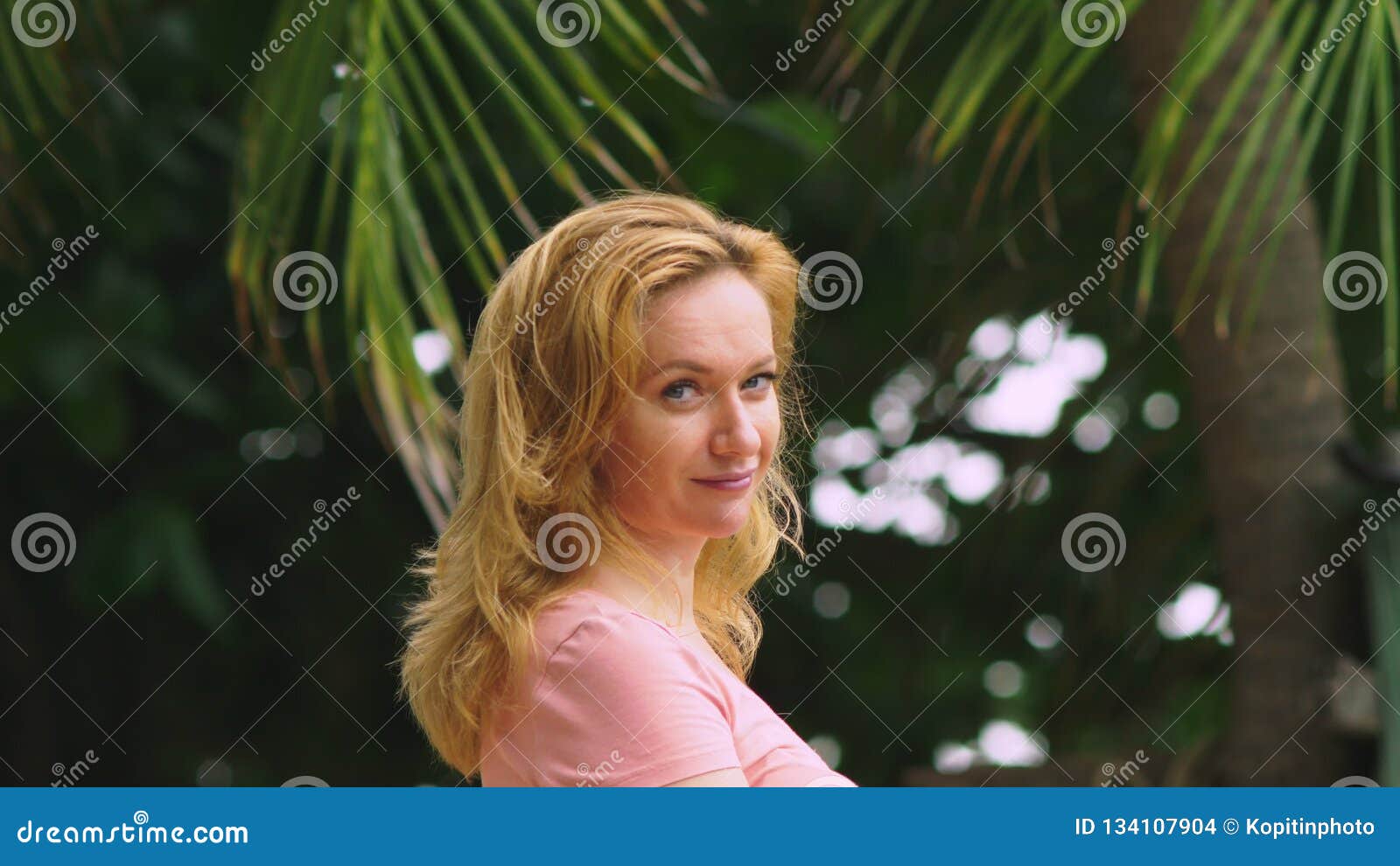 Beautiful Blond Woman Touches Her Hair In Nature And Looks At The