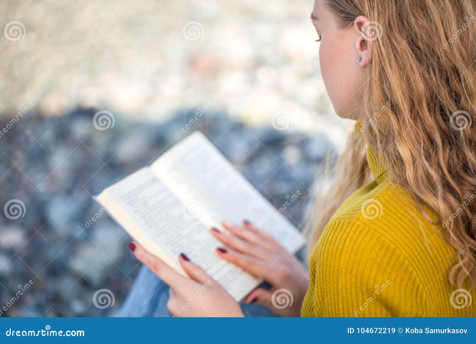 Beautiful Blonde Girl Is Reading A Book On The Beach Stock Image