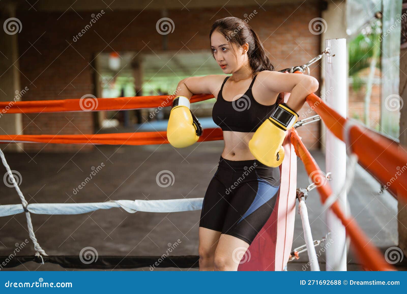 A Beautiful Boxer with Yellow Boxing Gloves Leaning on the Box Ring ...