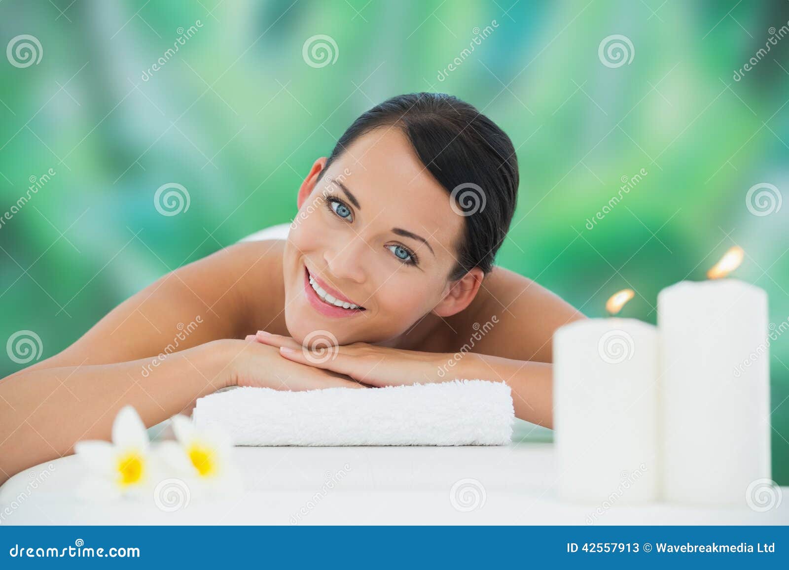 Beautiful Brunette Relaxing On Massage Table Smiling At Camera Stock