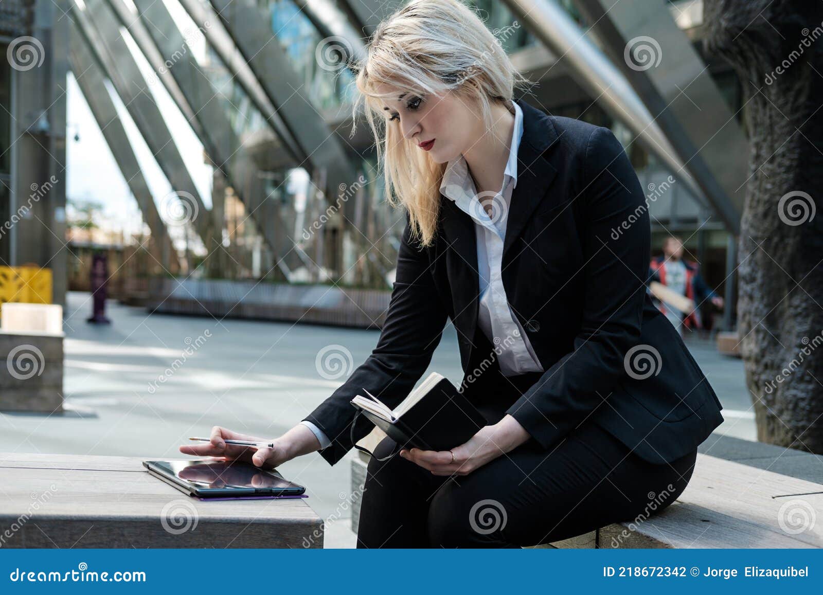 Business Woman Using a Tablet with a Notepad in the Other Hand Stock ...