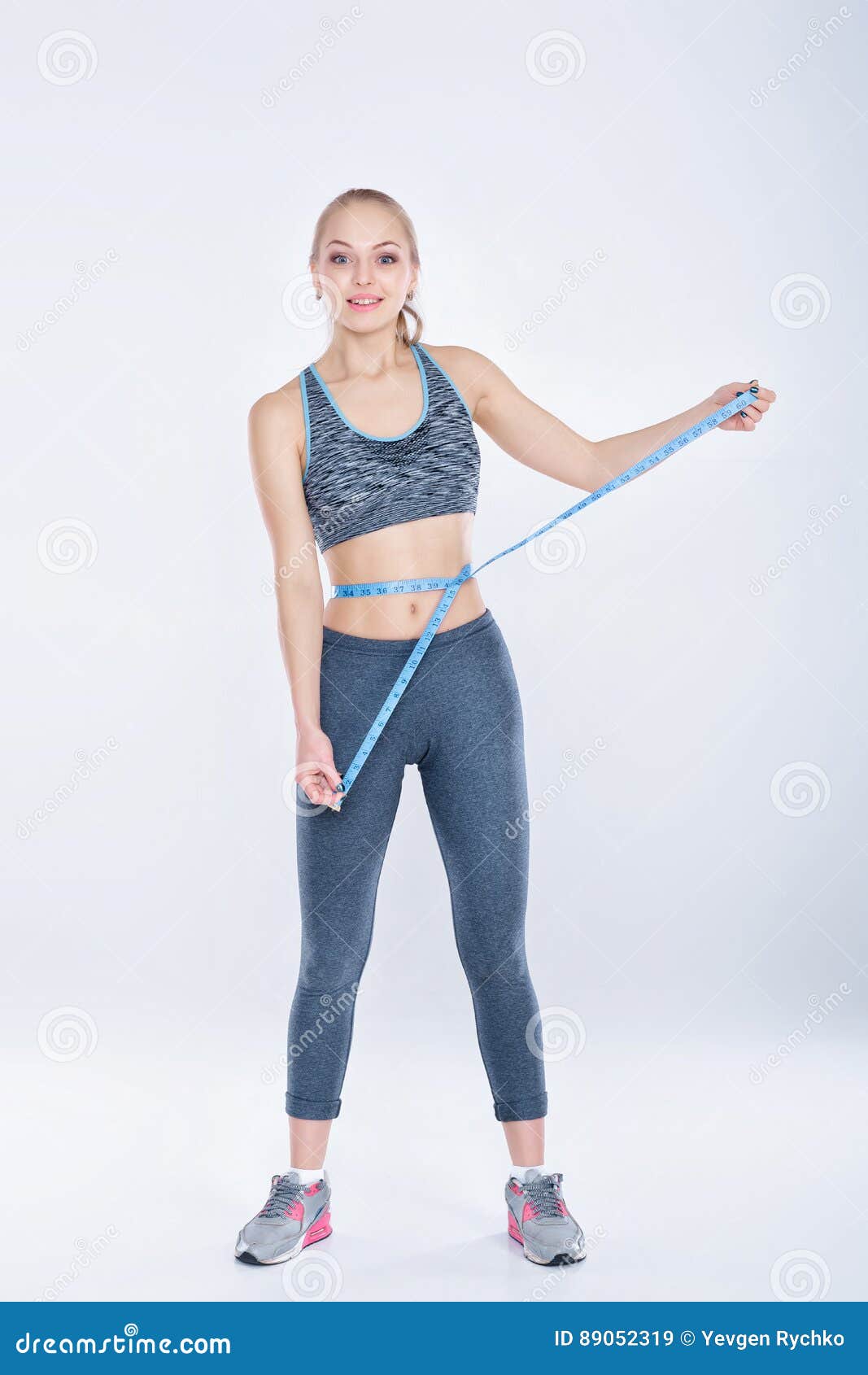 Beautiful Fitness Girl In Sportswear Measures Waist With Measuring Tape