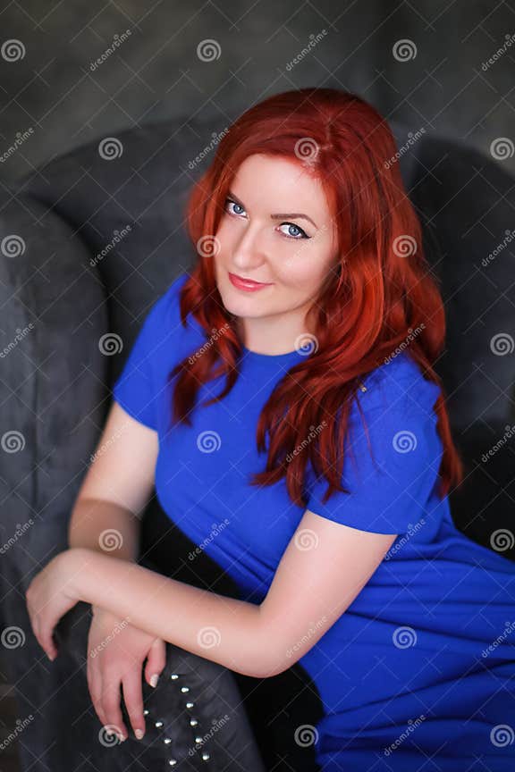 Beautiful Ginger Haired Woman In Blue Dress Sitting In Gray Armchair