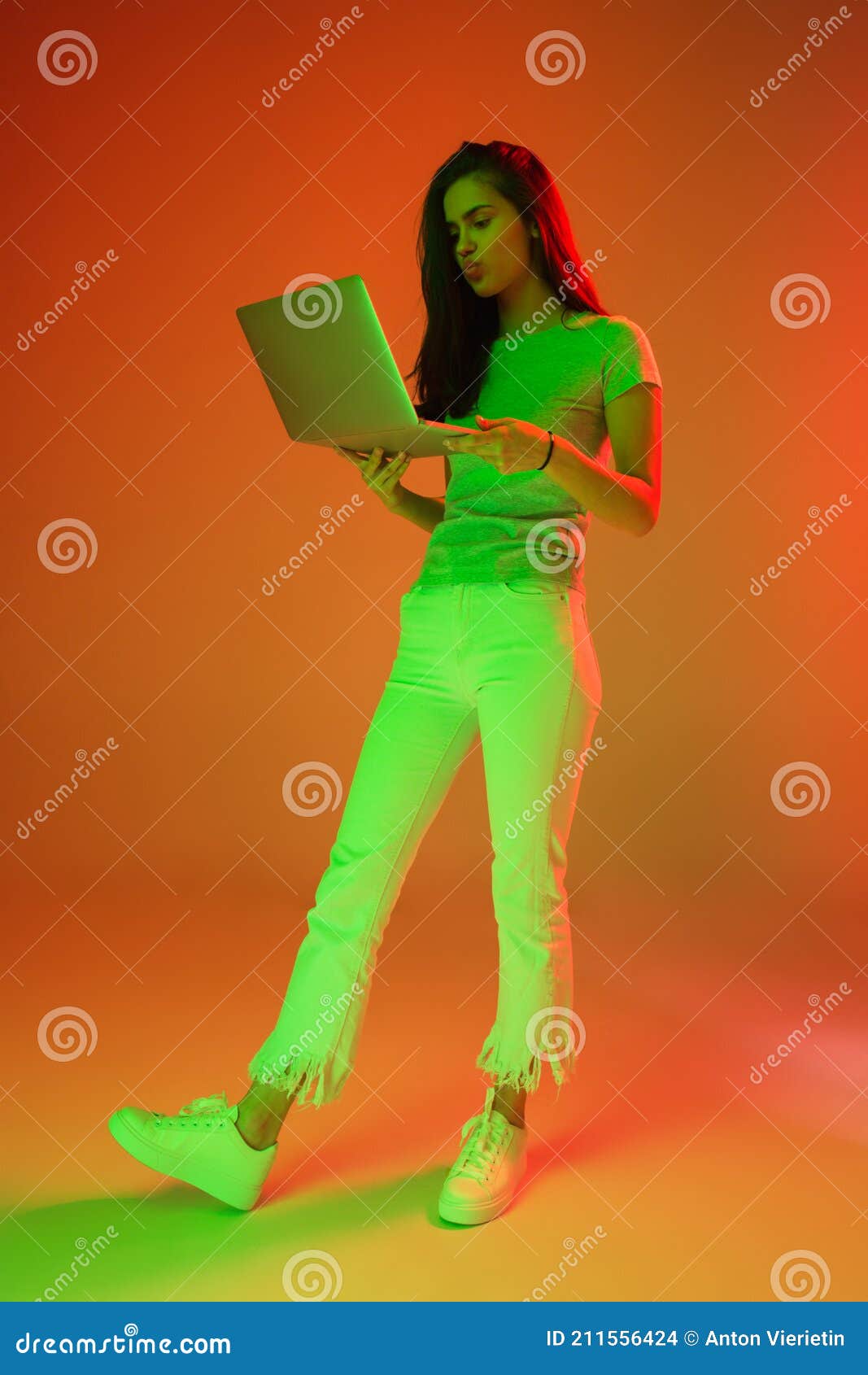 Beautiful Girl Using Laptop Isolated On Multicolored Background In Neon