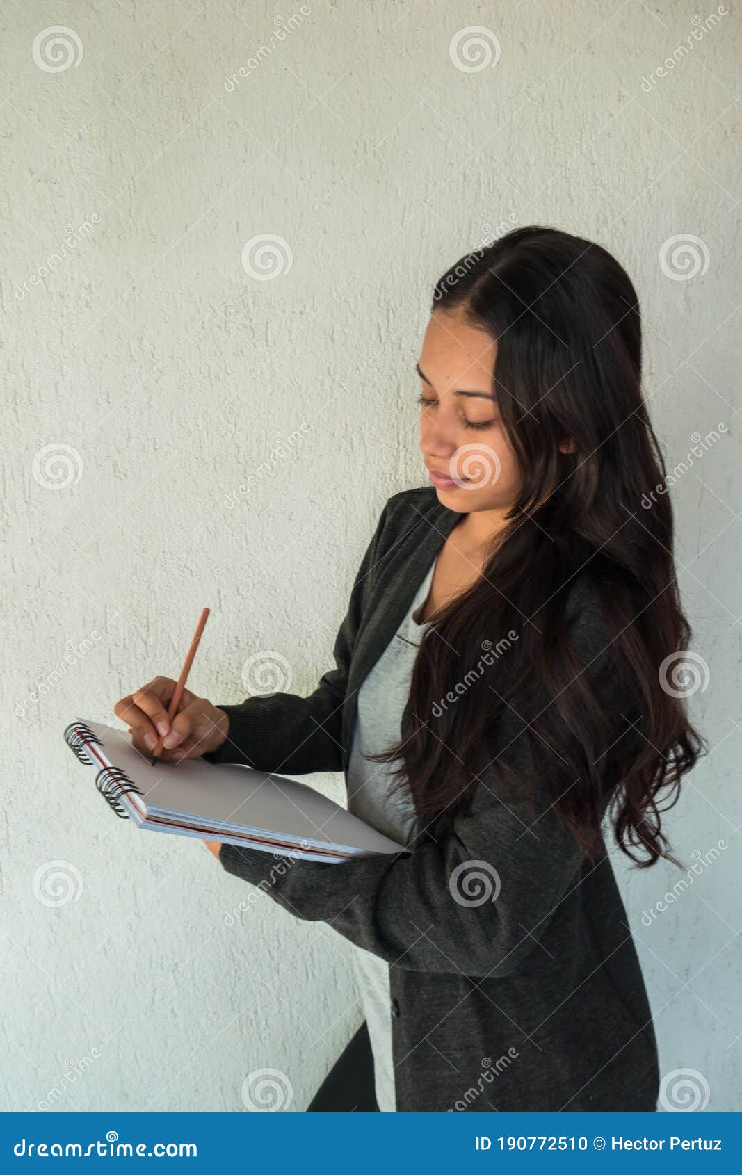 A Beautiful Hispanic Woman at Home Writing Notes while Holding a ...