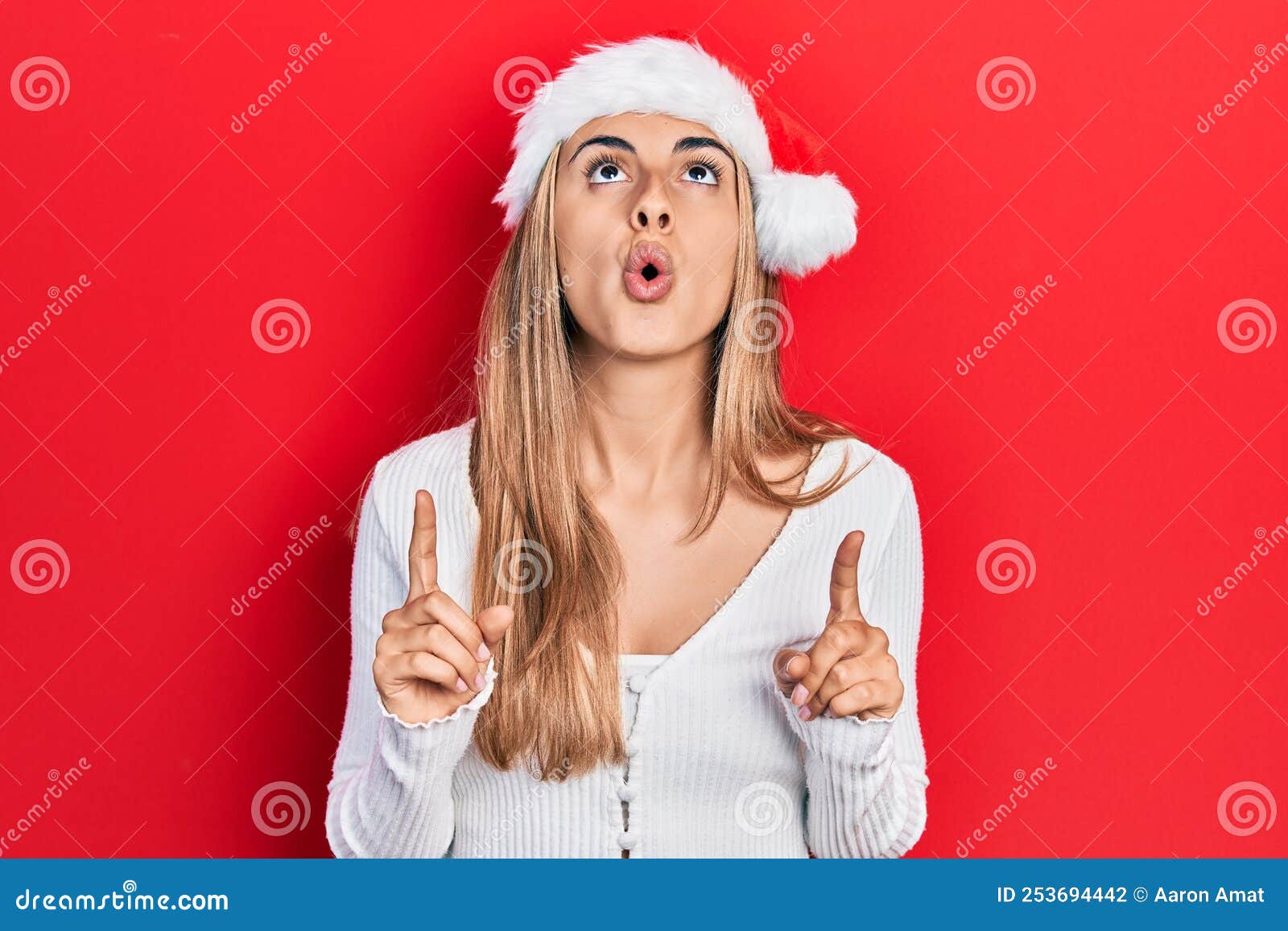Beautiful Hispanic Woman Wearing Christmas Hat Amazed And Surprised