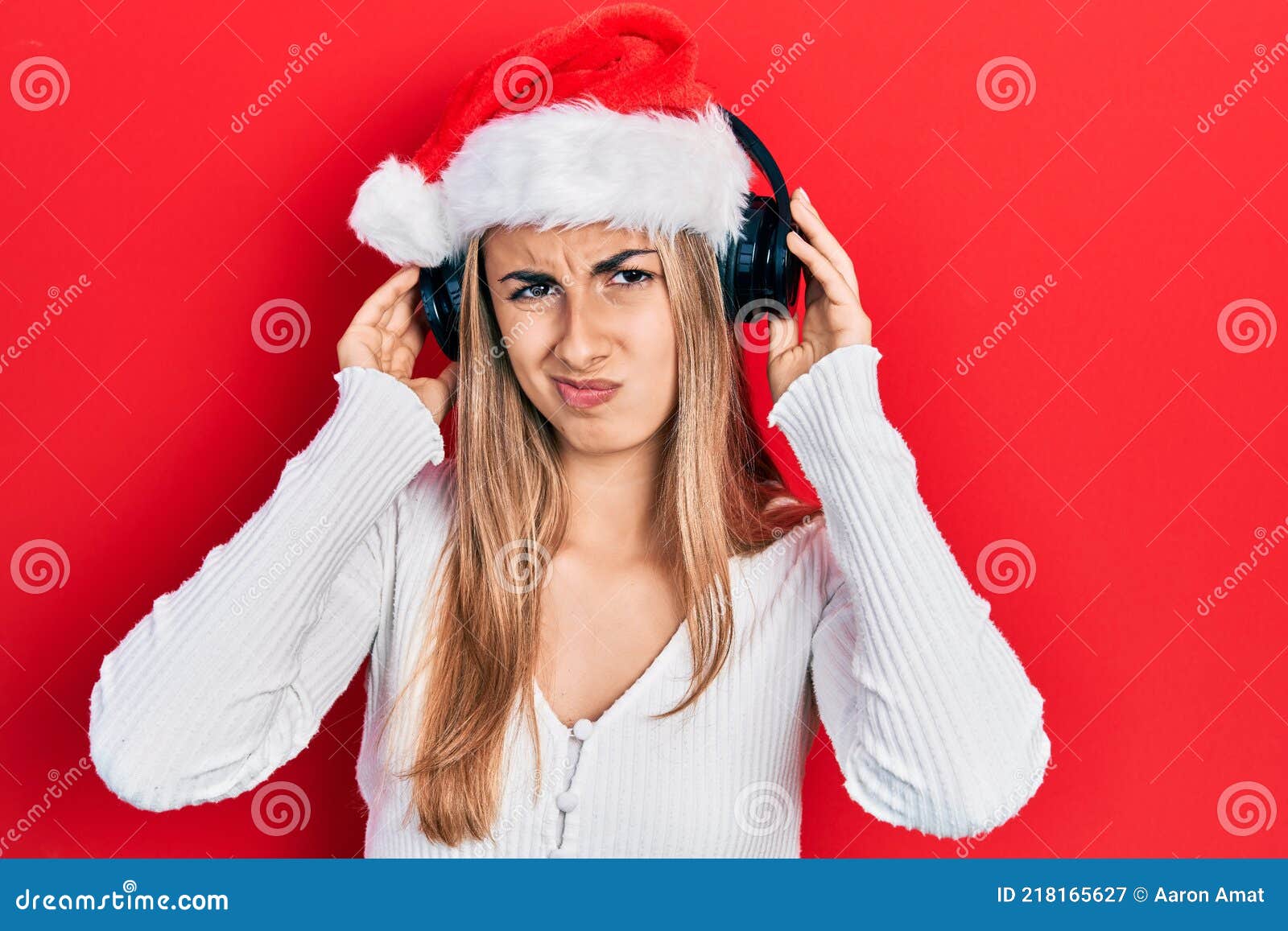 Beautiful Hispanic Woman Wearing Christmas Hat And Headphones Clueless
