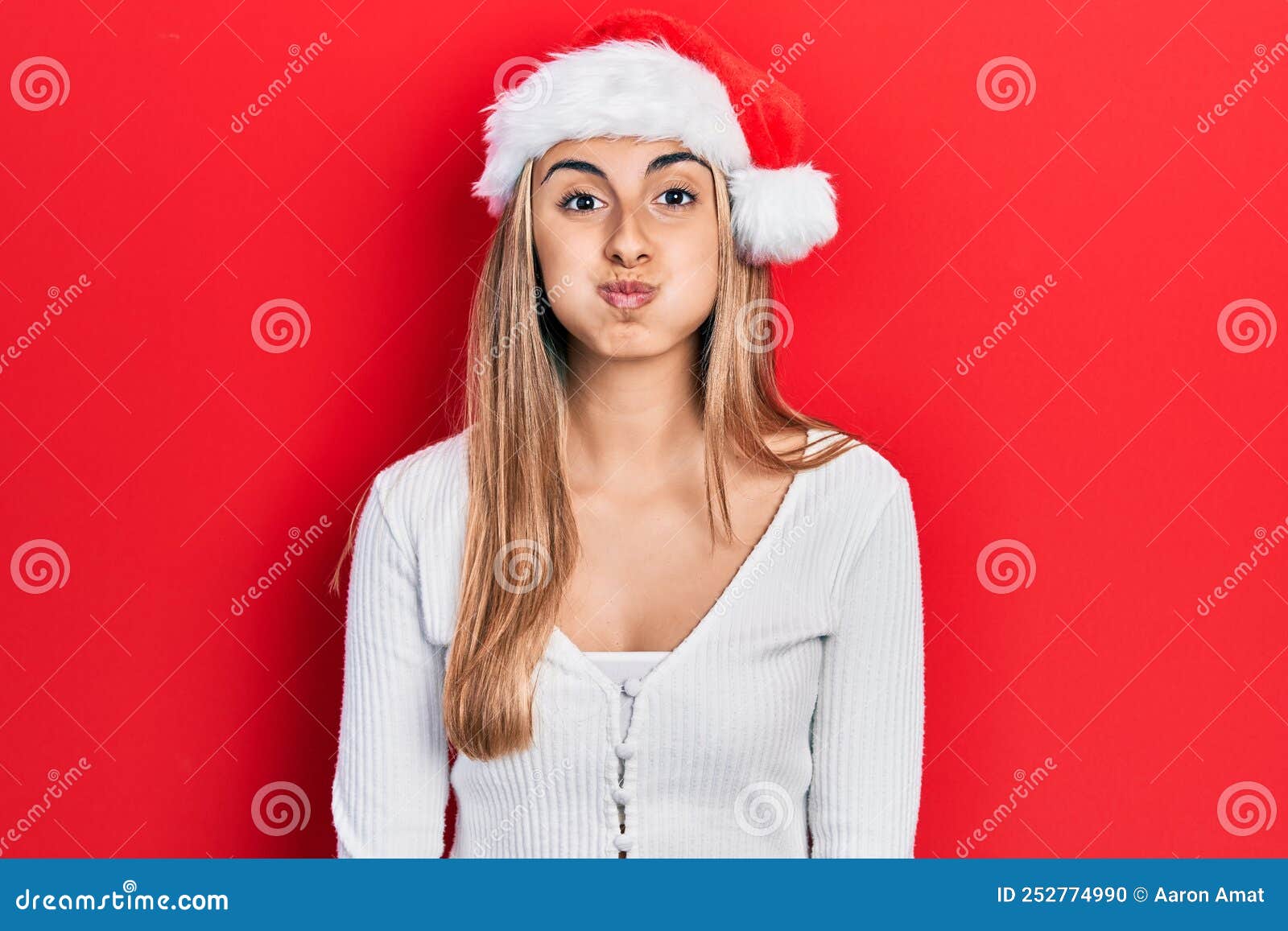 Beautiful Hispanic Woman Wearing Christmas Hat Puffing Cheeks With