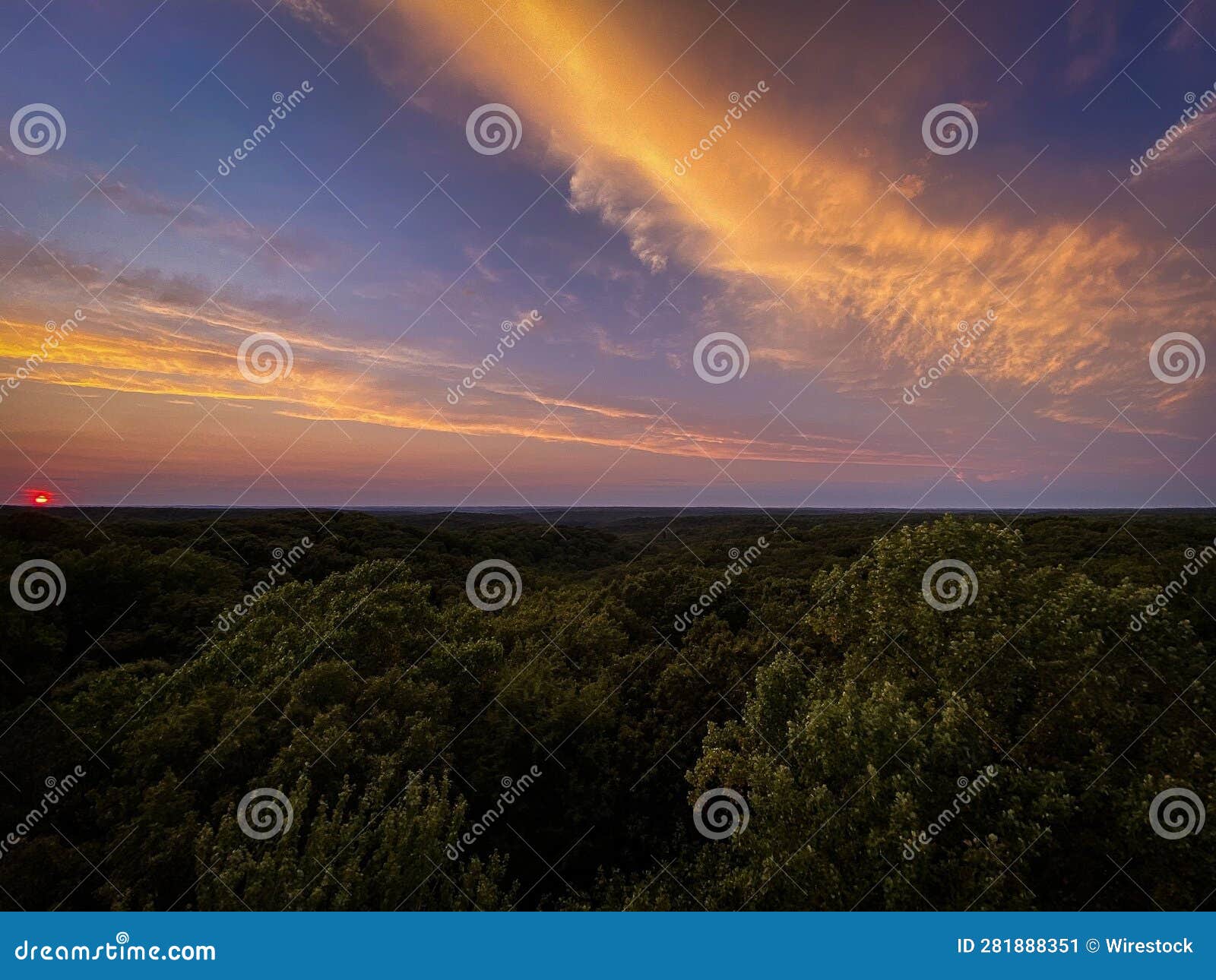 The Setting Sun is Set Over the Trees and Field Below Stock Image ...
