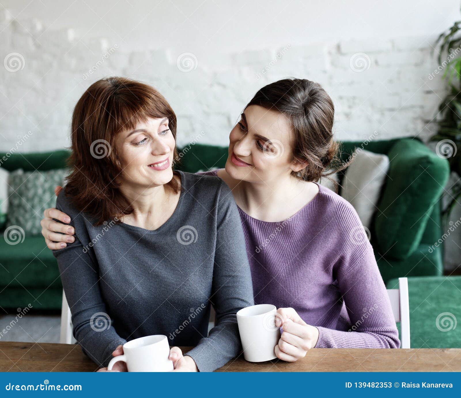 Beautiful Mature Mother And Her Adult Daughter Are Drinking Coffee
