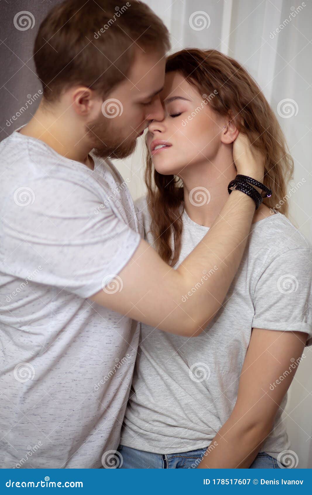 Handsome Man Kissing Beautiful And Brunette Woman In Bedroom Stock