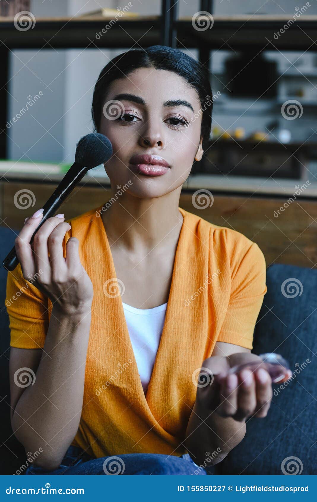 Beautiful Mixed Race Girl In Orange Shirt Applying Face Powder At Home