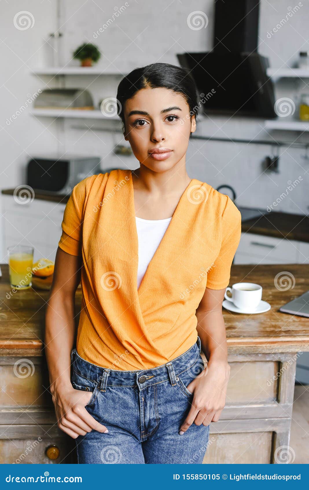 Beautiful Mixed Race Girl In Orange Shirt Standing In Kitchen And