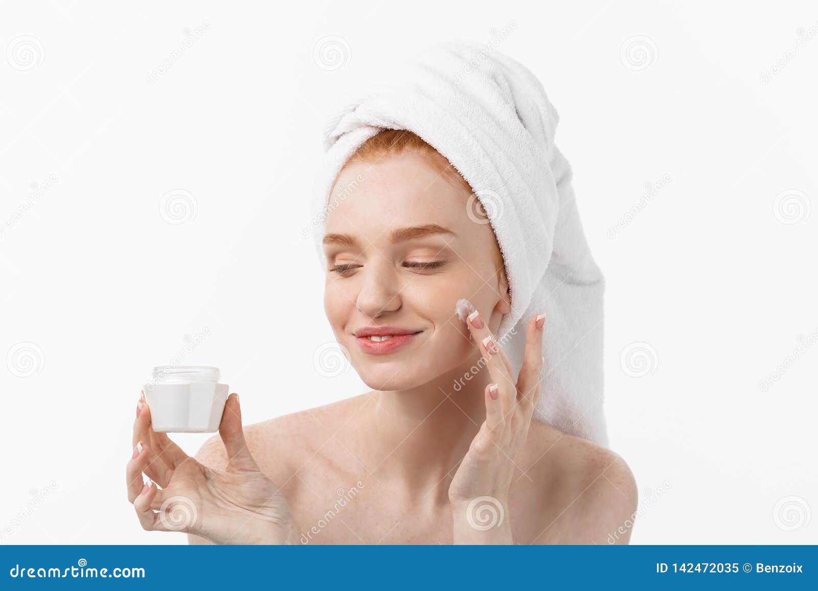 Beautiful Model Applying Cosmetic Cream Treatment On Her Face On White